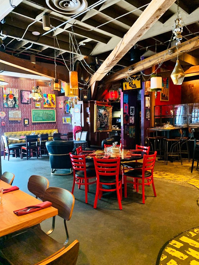 Red chairs pop against artistic chaos&mdash;dining here feels like eating inside a painter's imagination after they've had their morning coffee.