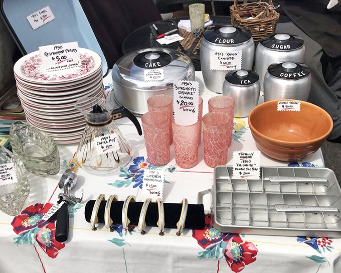 Grandmother's kitchen, carefully curated. Pink crackle glasses and aluminum canisters labeled "FLOUR" and "SUGAR" await their retro revival moment.