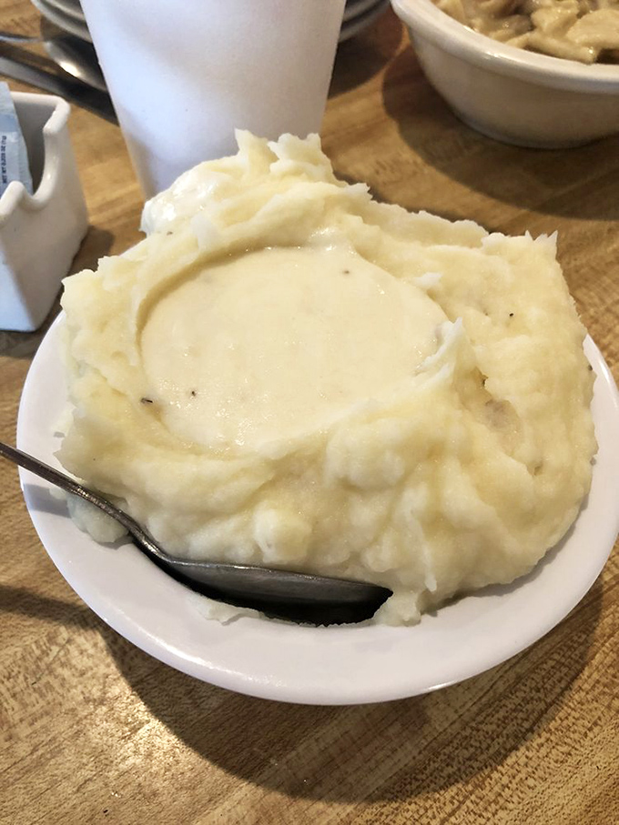 Mashed potatoes sculpted into a cloud-like crater, waiting patiently to become a gravy reservoir of epic proportions.