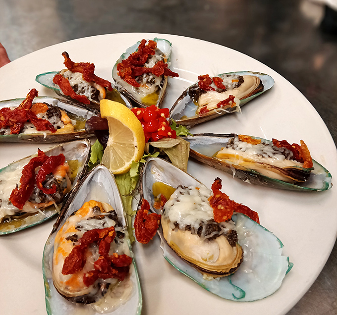 These mussels aren't just seafood&mdash;they're little boats delivering sun-dried tomatoes and cheese directly to your happiness receptors. The lemon stands by, ready for duty.