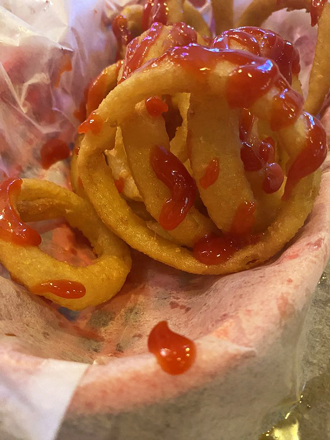 Onion rings wearing their Sunday best &ndash; perfectly battered, golden-fried, and drizzled with ketchup. Like edible jewelry for your basket.