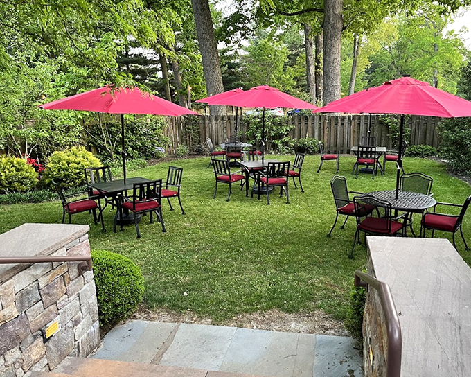 The outdoor dining area, with its vibrant red umbrellas, offers a garden oasis where summer breezes complement every bite – nature's dining room, upgraded.