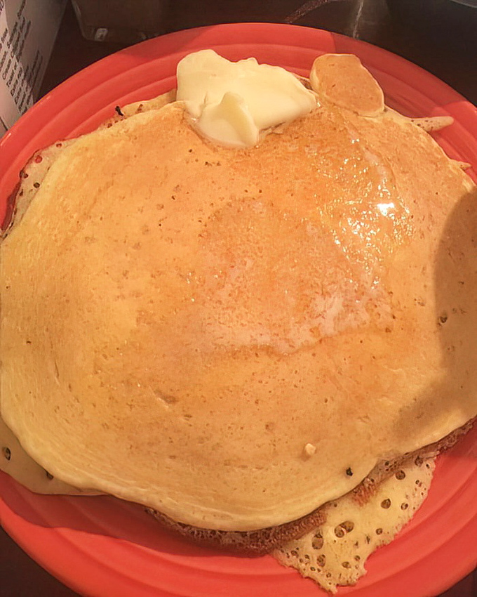 Golden pancakes that catch the light like sunrise, topped with a melting pat of butter awaiting maple destiny.