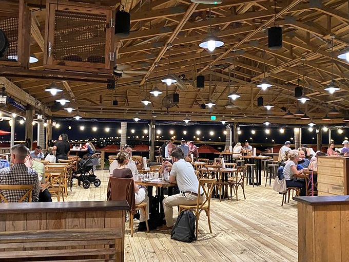 As night falls, the pavilion transforms from casual eatery to waterfront dining cathedral, with string lights standing in for stars.