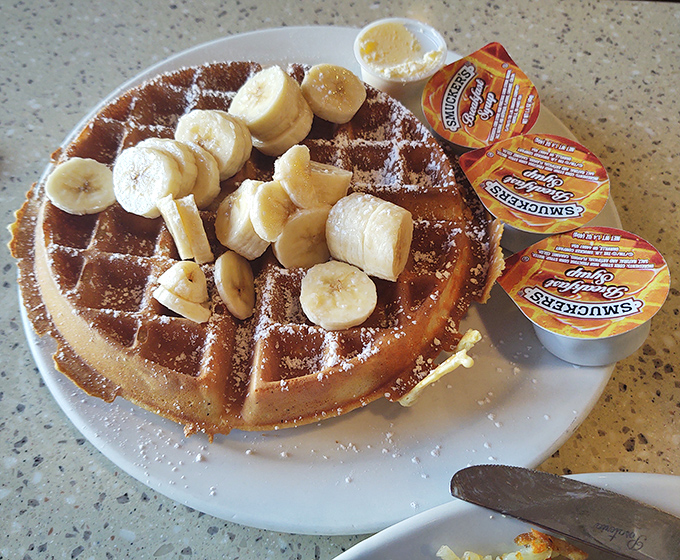 A golden waffle crowned with sliced bananas and waiting for its maple syrup baptism. Breakfast doesn't get more photogenic than this.