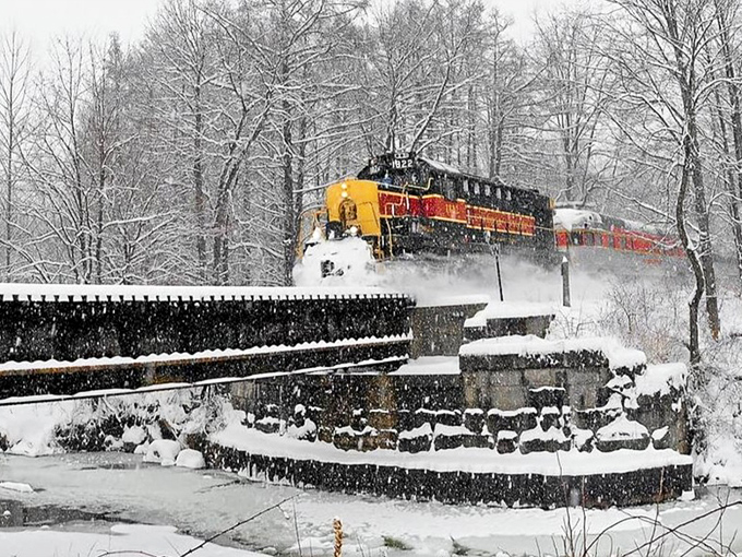 Winter transforms the railroad into a snow globe fantasy, with the bright locomotive cutting through pristine white landscapes like a hot knife through butter.