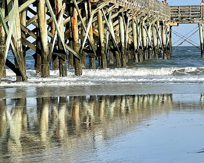 The wooden pier creates a perfect reflection on wet sand. Nature's symmetry at work, proving the best things in life require no admission fee.