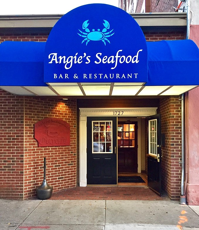 Angie's blue awning and crab logo create the perfect neighborhood beacon for authentic Baltimore seafood done with genuine care.