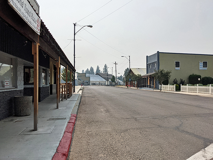 White picket dreams! Portola's empty street stretches toward possibility, flanked by buildings that have witnessed more history than your grandmother's photo albums.
