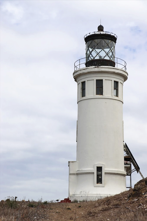 Rugged cliffs plunge dramatically into azure waters while the distant lighthouse adds that perfect human touch to nature's masterpiece.