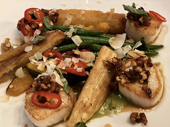 Seared scallops share the plate with colorful vegetables in a composition so beautiful you almost feel guilty disturbing it. Almost.