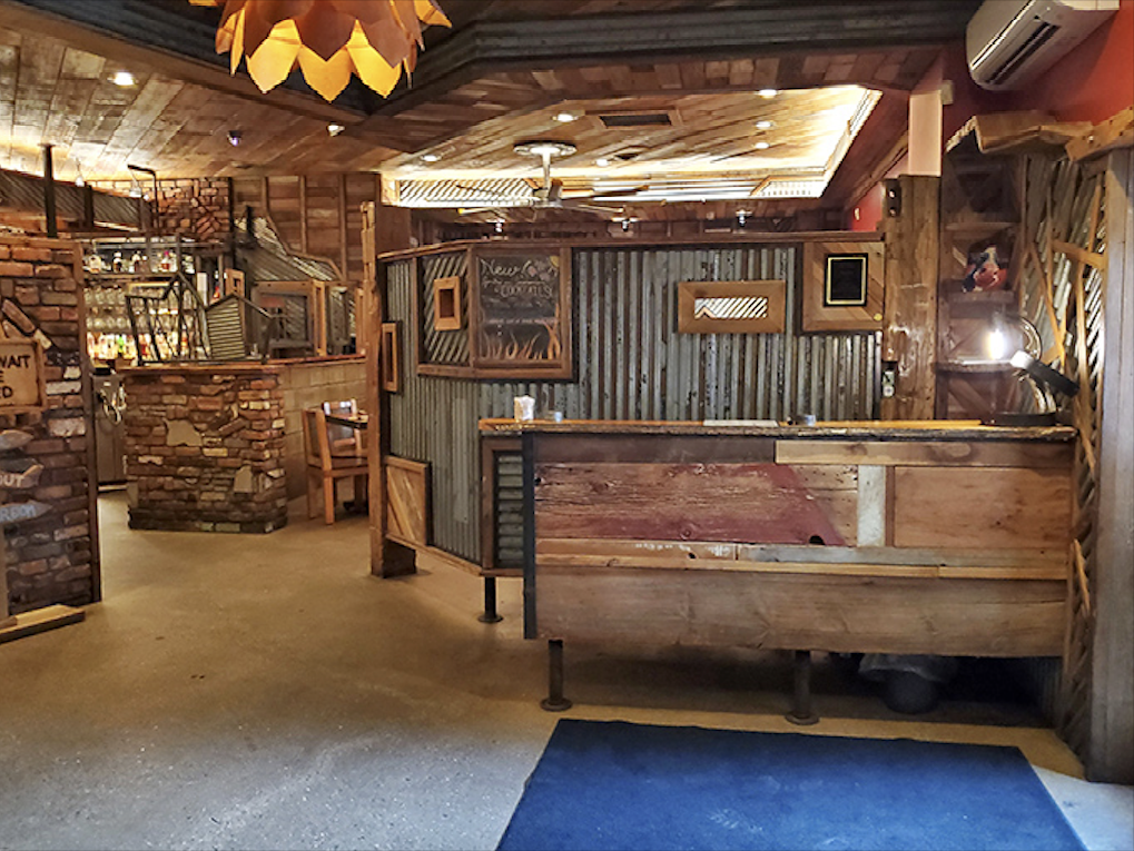 Rustic meets refined in this thoughtfully designed interior where corrugated metal, reclaimed wood, and stone create the perfect backdrop for serious barbecue business.