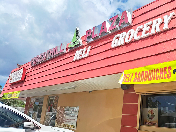 The vibrant red exterior of Forest Hills Plaza Grocery stands out like a culinary beacon, promising deli delights within its unassuming walls.