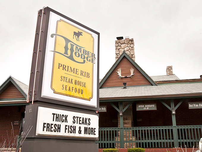 The iconic yellow sign beckons hungry travelers like a lighthouse for carnivores, promising thick steaks and seafood treasures in rustic woodland surroundings.