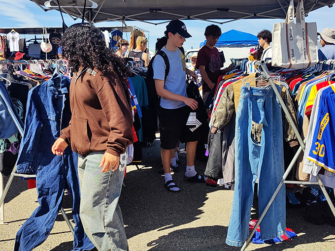 Denim heaven for the fashion archaeologist! Young shoppers sift through racks of vintage jackets and jeans, hunting for that perfect worn-in treasure.