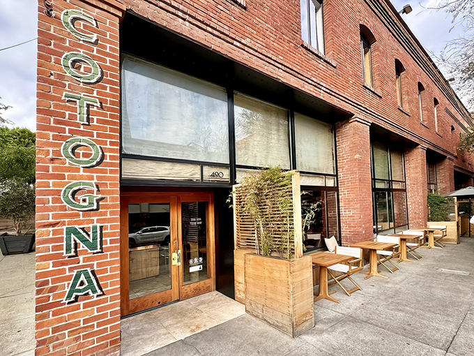 The iconic brick exterior of Cotogna, where that vertical lettering practically whispers, "Come inside, we've got pasta that will change your life."