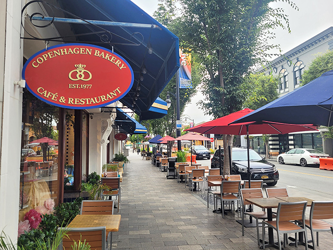 The iconic red oval sign welcomes you to Copenhagen Bakery & Cafe, where Burlingame Avenue's charm meets authentic Danish delights.