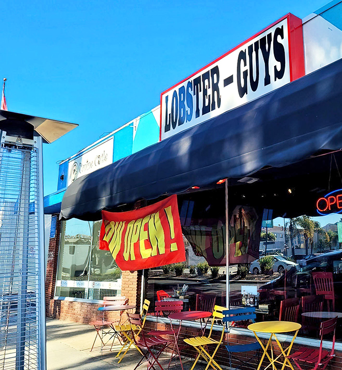 Colorful outdoor seating creates a cheerful seafood oasis on the sidewalk, where the bright yellow and red tables promise a casual feast under California's perfect blue skies.