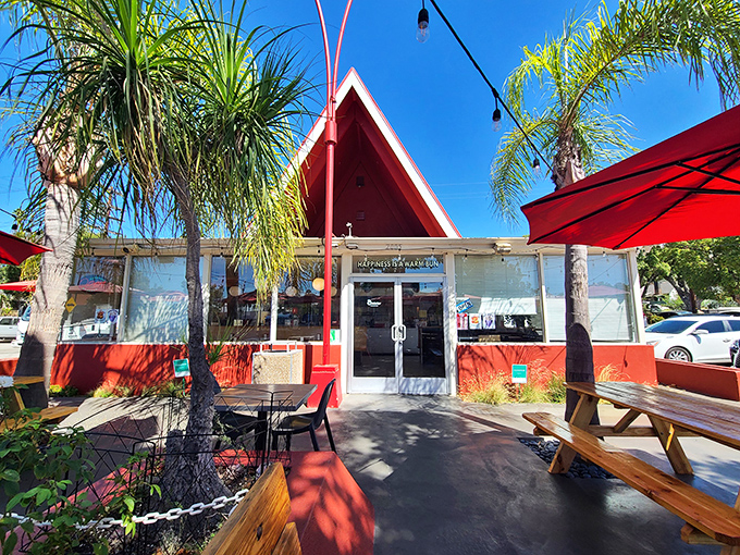 The iconic red A-frame beckons like a burger lighthouse, promising delicious refuge from ordinary fast food under the California sun.