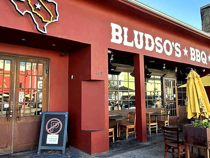 The iconic red exterior of Bludso's BBQ stands like a beacon of hope for hungry souls seeking smoky salvation in Los Angeles.