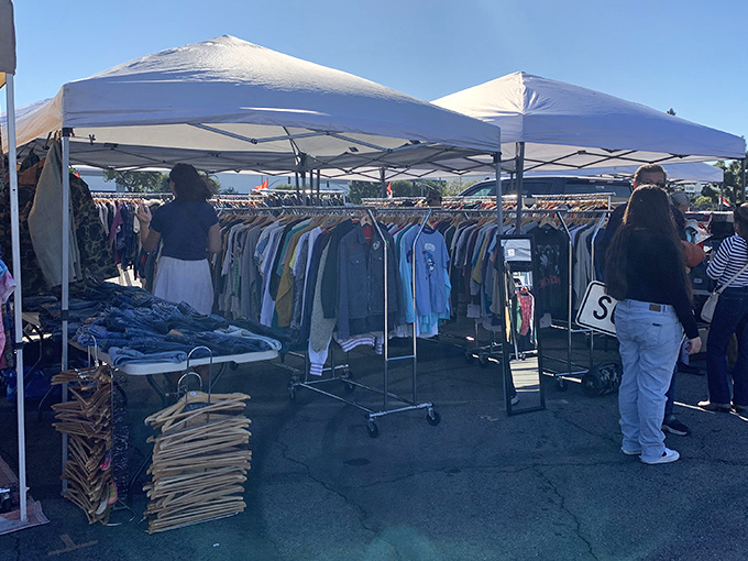 Treasure hunters navigate racks of vintage clothing under white canopy tents, where yesterday's fashion becomes tomorrow's statement piece.
