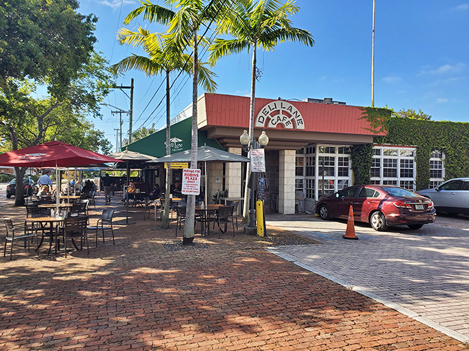 The welcoming patio at Deli Lane Cafe invites you to linger over breakfast beneath swaying palms, where South Miami's brick-paved charm meets morning sunshine.