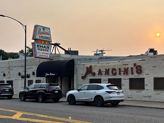 The iconic Mancini's sign glows against the twilight sky, a beacon of culinary tradition on West 7th Street that's been guiding hungry St. Paulites home for generations.