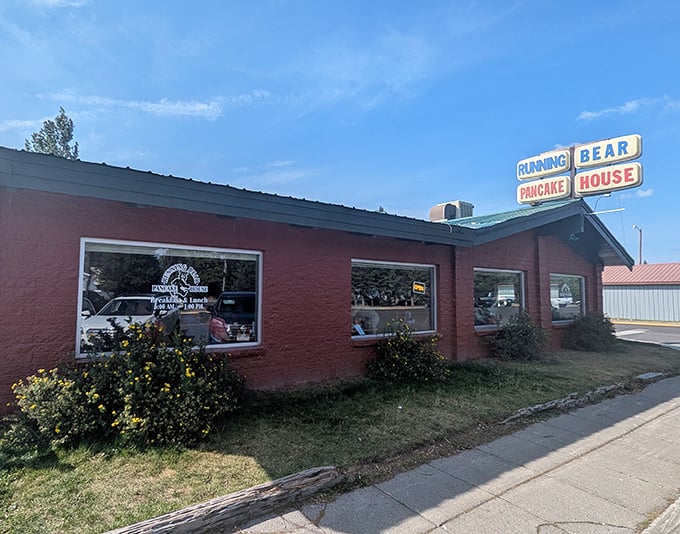 The iconic red brick exterior of Running Bear Pancake House stands like a breakfast beacon against Montana's big sky, promising pancake perfection within.