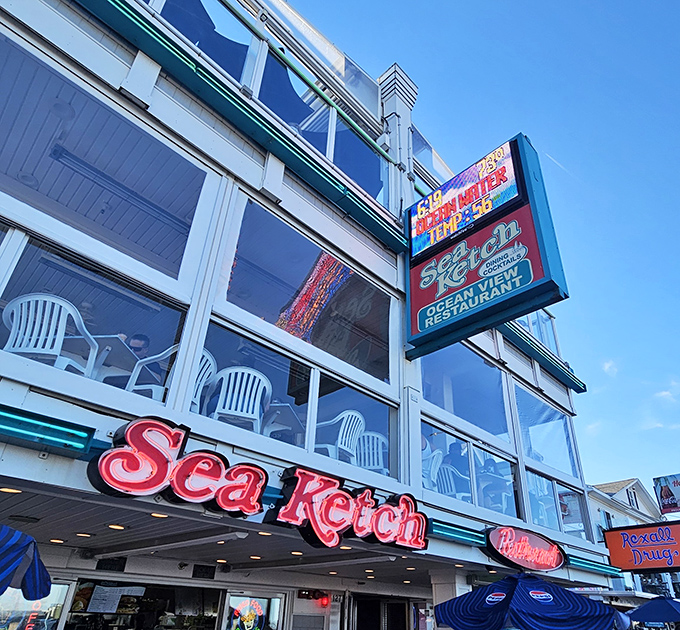 The iconic Sea Ketch sign glows like a beacon for hungry souls. Those white plastic chairs on the deck promise front-row seats to seafood paradise.