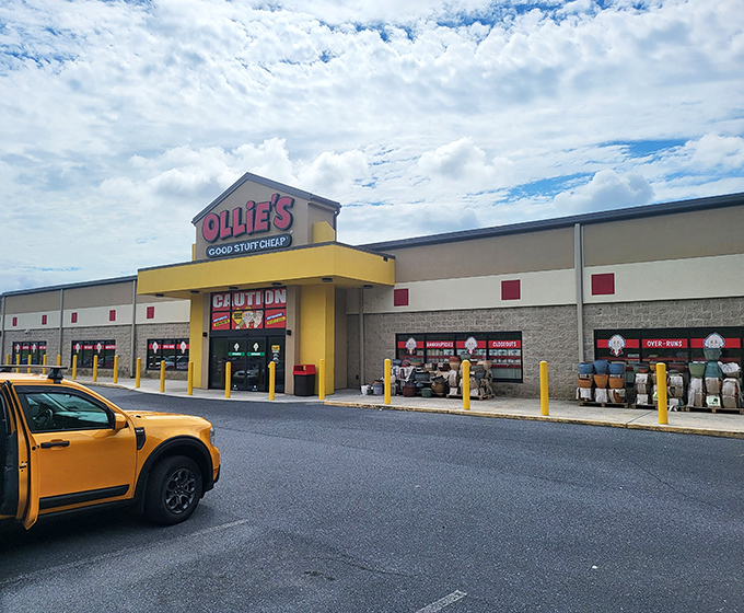 Blue skies frame Ollie's distinctive entrance, where the bright yellow awning serves as a beacon for savvy shoppers seeking serious savings.
