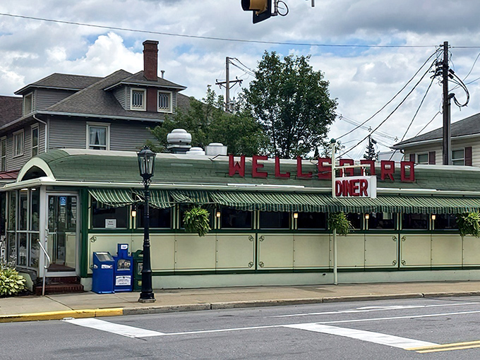 The green and cream exterior of Wellsboro Diner stands like a time capsule on Main Street, its vintage awnings and bold red signage beckoning hungry travelers from miles around.