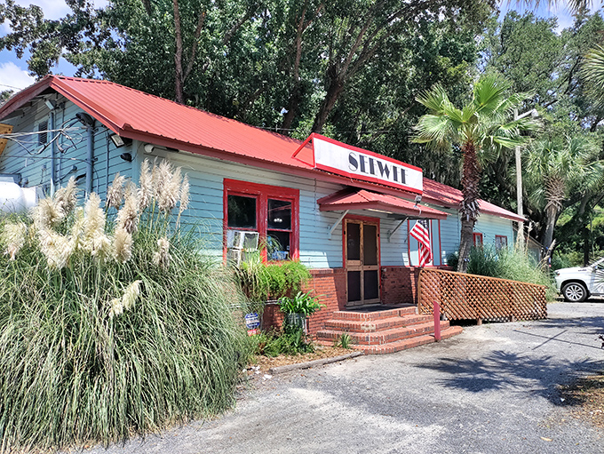 The light blue exterior with red trim stands like a coastal sentinel among the palmettos, promising seafood treasures within. No fancy facade needed when the food speaks volumes.