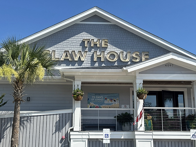The Claw House stands proudly against Carolina blue skies, its weathered gray exterior and bold signage promising seafood treasures within.
