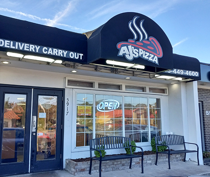 The unassuming storefront of AJ's Pizza beckons with its simple black awning and welcoming benches &ndash; proof that culinary treasures often hide in plain sight.