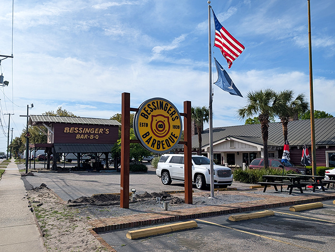 The iconic yellow and brown sign stands like a barbecue beacon along Savannah Highway, promising smoky delights beneath those American and South Carolina flags.