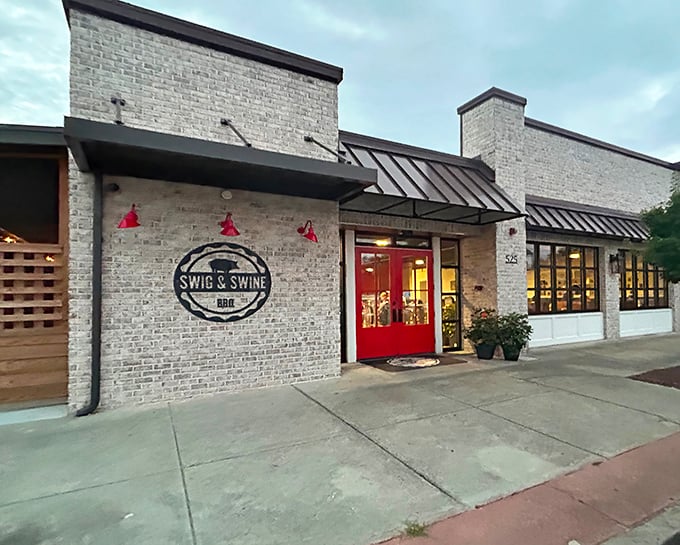 The unassuming brick exterior with that pop of red door is like a secret handshake – those who know, know this is where barbecue magic happens.