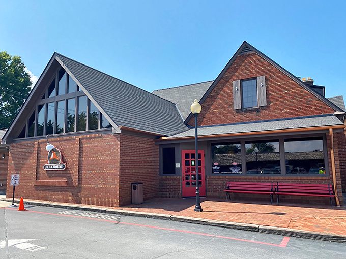 The historic brick exterior of The Firehouse Restaurant stands as a mouthwatering beacon for barbecue pilgrims, complete with its signature red bench for pre-meal anticipation.