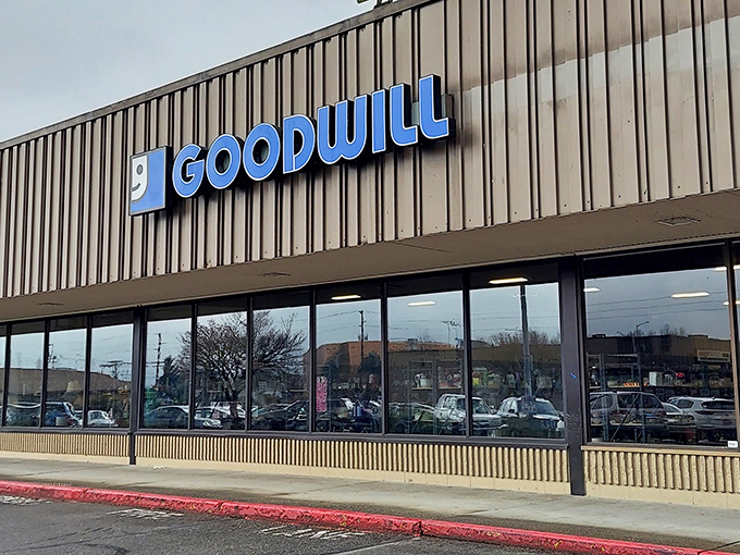 The blue Goodwill sign stands out against the brown exterior like a beacon for bargain hunters, promising treasures waiting to be discovered inside.