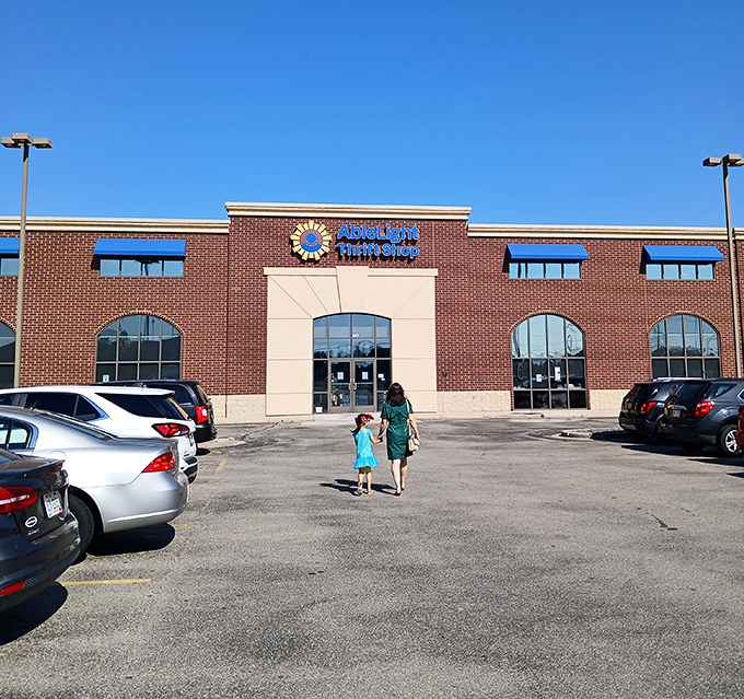The brick facade of AbleLight Thrift Shop welcomes bargain hunters with its distinctive blue awnings and promise of treasures waiting inside.