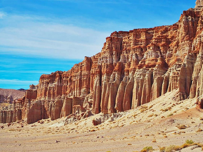 Nature's own cathedral: these towering red cliffs stand like sentinels against the desert sky, a geological masterpiece millions of years in the making.