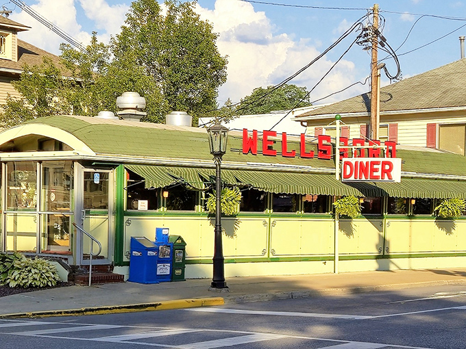 The green and cream exterior of Wellsboro Diner stands like a time capsule on Main Street, its vintage awnings and bold red signage beckoning hungry travelers from miles around.