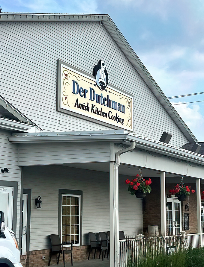 The classic white siding and welcoming porch of Der Dutchman stands as a beacon of comfort food in Walnut Creek, where hanging flower baskets add splashes of color to Amish simplicity.