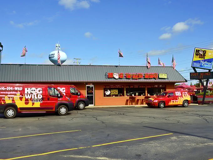 The bright red exterior of Hog Wild BBQ stands like a beacon for meat lovers, complete with flame-adorned delivery vehicles ready to spread smoky joy throughout Holland.