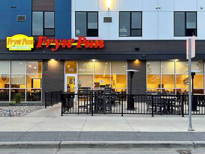 The bright red Fryn' Pan sign glows like a beacon for hungry travelers, promising comfort food salvation on Fargo's Main Avenue.