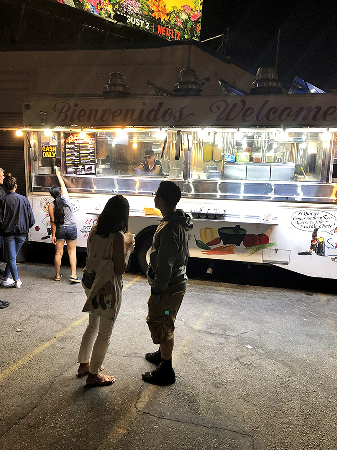 The nightly pilgrimage begins at El Chato's glowing window, where patient taco devotees line up for their reward. Worth every minute of waiting.