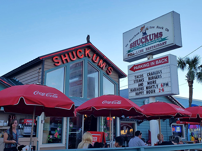 The iconic blue exterior of Shuckums with its bright red signage promises seafood treasures within. Those Coca-Cola umbrellas have sheltered countless happy diners.