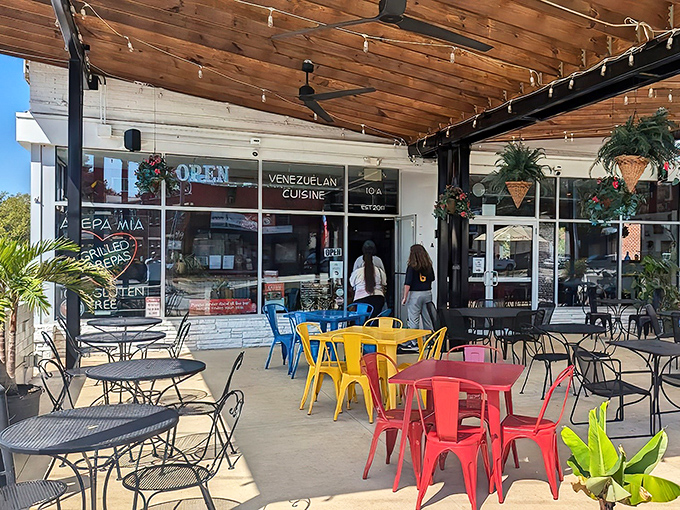 Venezuelan paradise found! Arepa Mia's vibrant outdoor seating area beckons with a rainbow of metal chairs under rustic wooden beams&mdash;an irresistible invitation to culinary adventure.