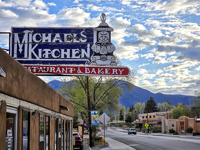 The iconic blue sign of Michael's Kitchen stands like a beacon against Taos' mountain backdrop, promising culinary salvation to hungry travelers and locals alike.