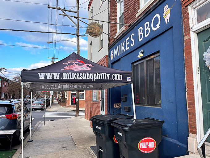 The blue storefront of Mike's BBQ stands like a beacon of smoky promise on this Philadelphia street corner, complete with their signature cartoon pig mascot.