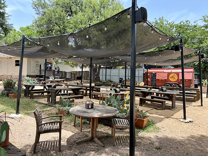 Shade canopies and string lights transform this rustic outdoor space into a barbecue oasis. It's where strangers become friends over the universal language of smoked meat excellence.